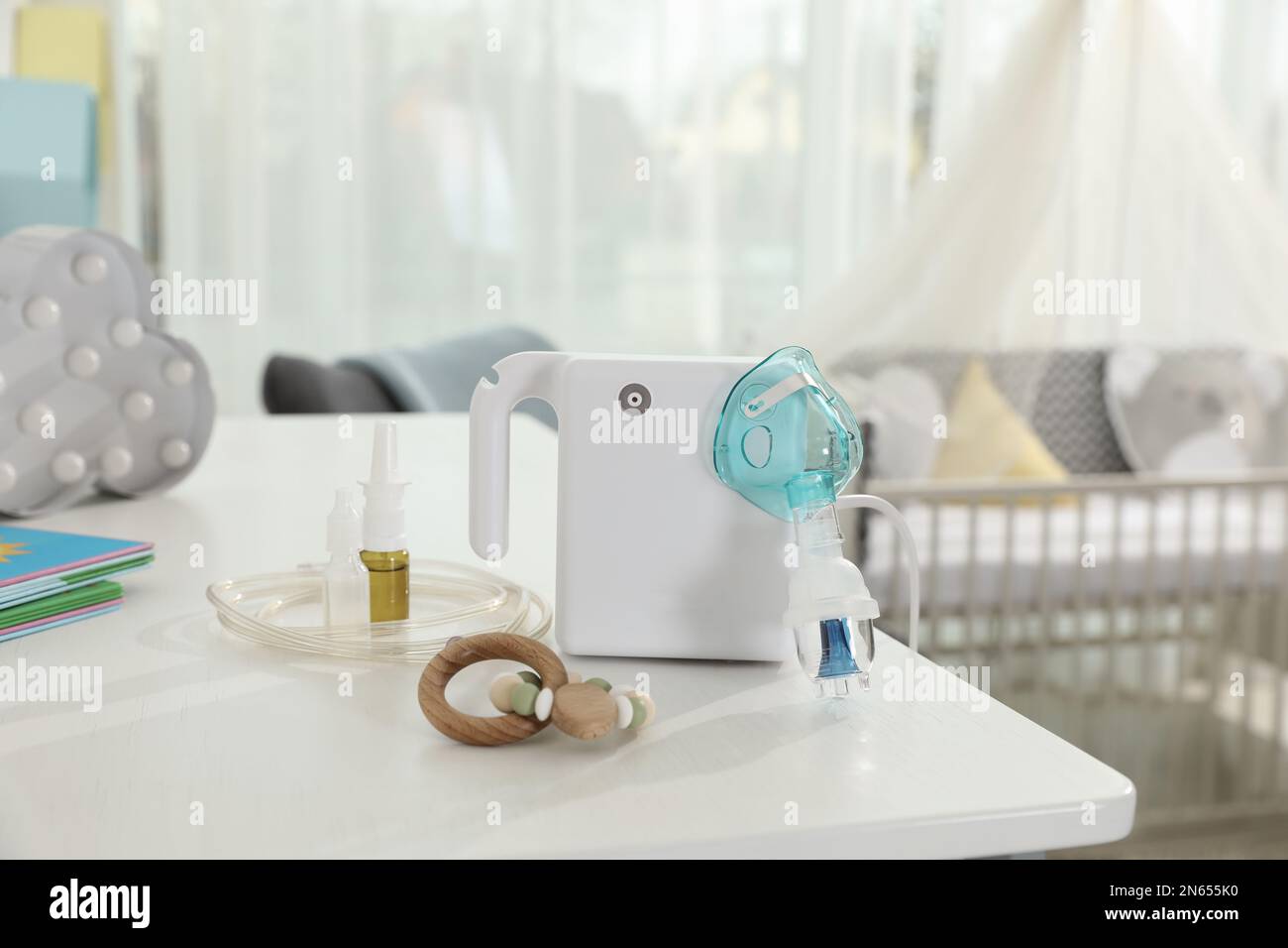 Modern nebulizer, medicines and wooden baby toy on white table in ...