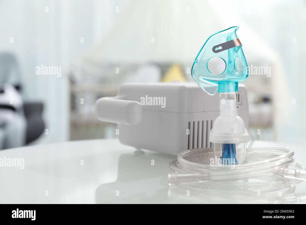Modern nebulizer with face mask on white table in children's room ...