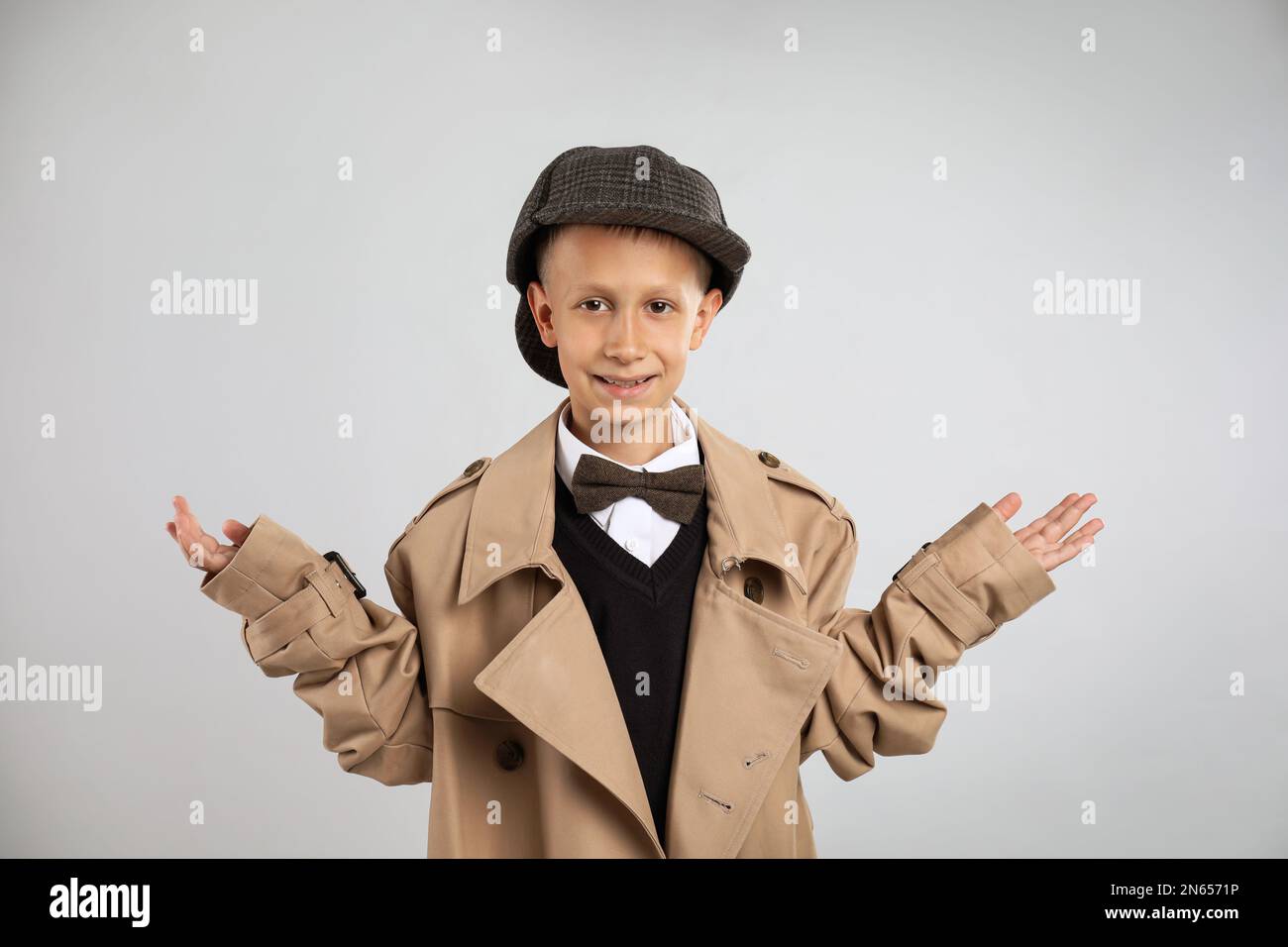 Cute little detective in hat and coat on grey background Stock Photo ...
