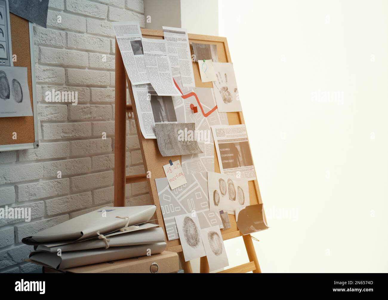 Board with fingerprints, crime scene photos and map near white brick ...
