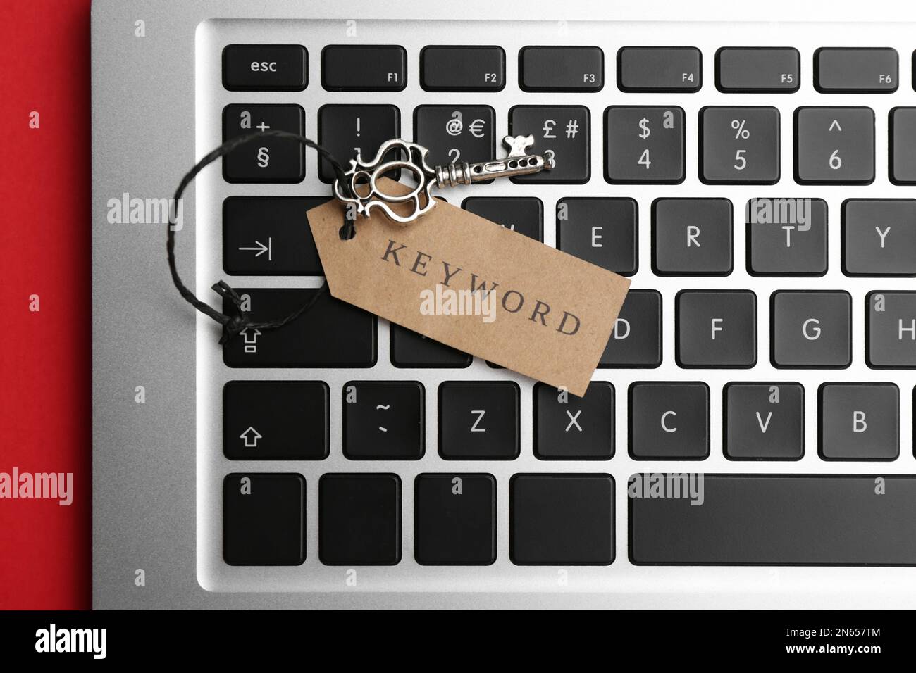 Laptop, vintage key and tag with word KEYWORD on red background, top ...