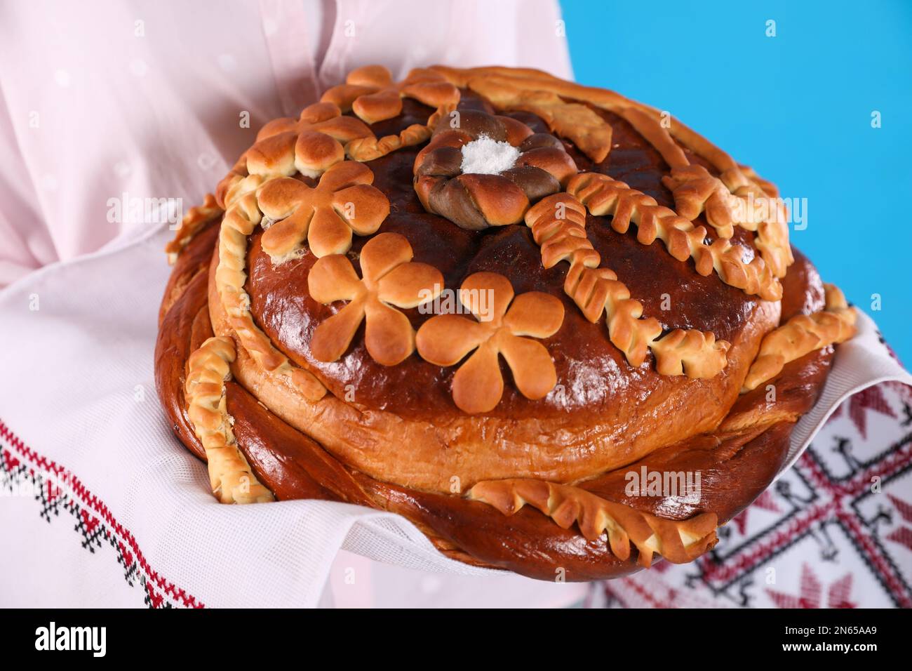 Woman with korovai on light blue background, closeup. Ukrainian bread ...