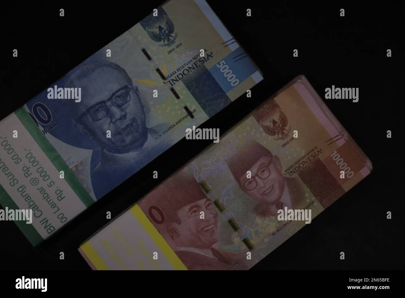 stacks of IDR 100,000 and IDR 50,000 rupiah banknotes on black ...