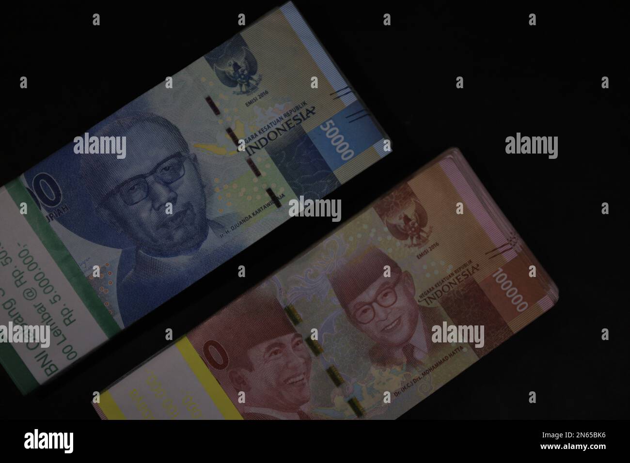 stacks of IDR 100,000 and IDR 50,000 rupiah banknotes on black ...