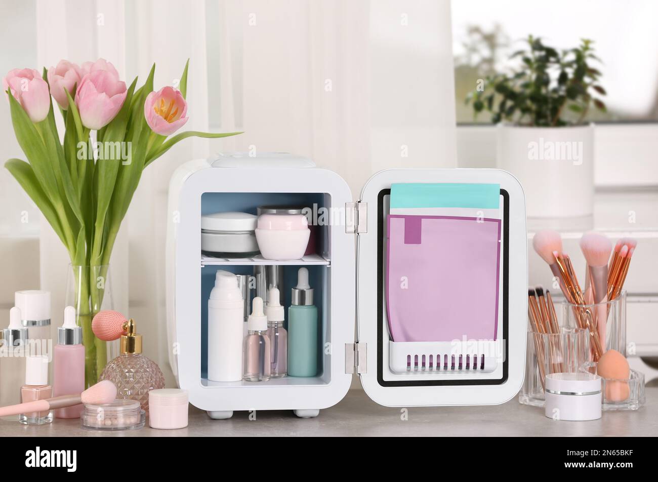 Open mini cosmetics refrigerator and skin care products on table Stock ...