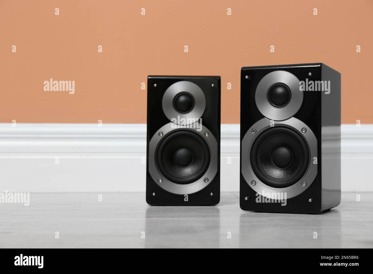 Modern powerful audio speakers on floor near orange wall Stock Photo ...