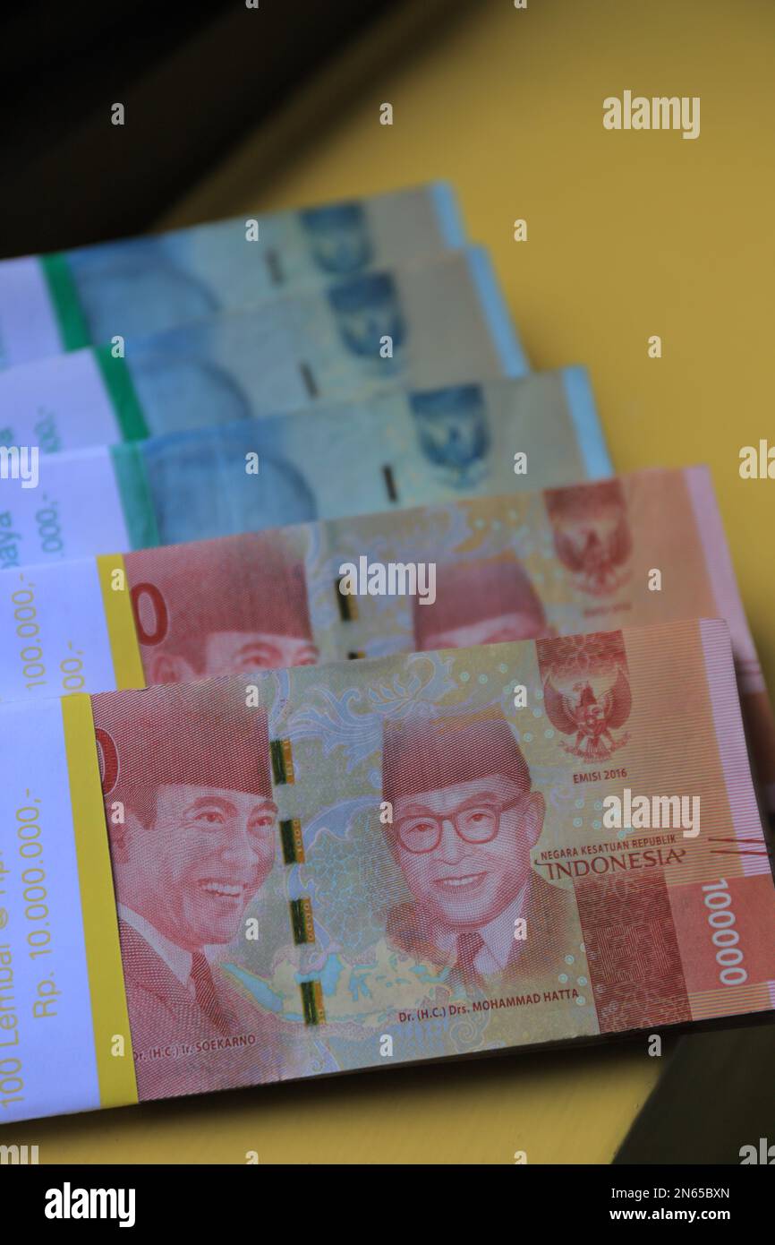 stacks of IDR 100,000 and IDR 50,000 rupiah banknotes on black ...