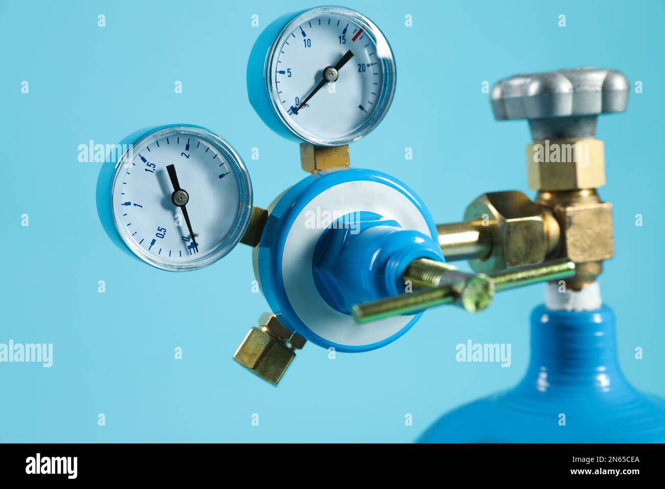 Pressure gauge of medical oxygen tank on light blue background, closeup ...