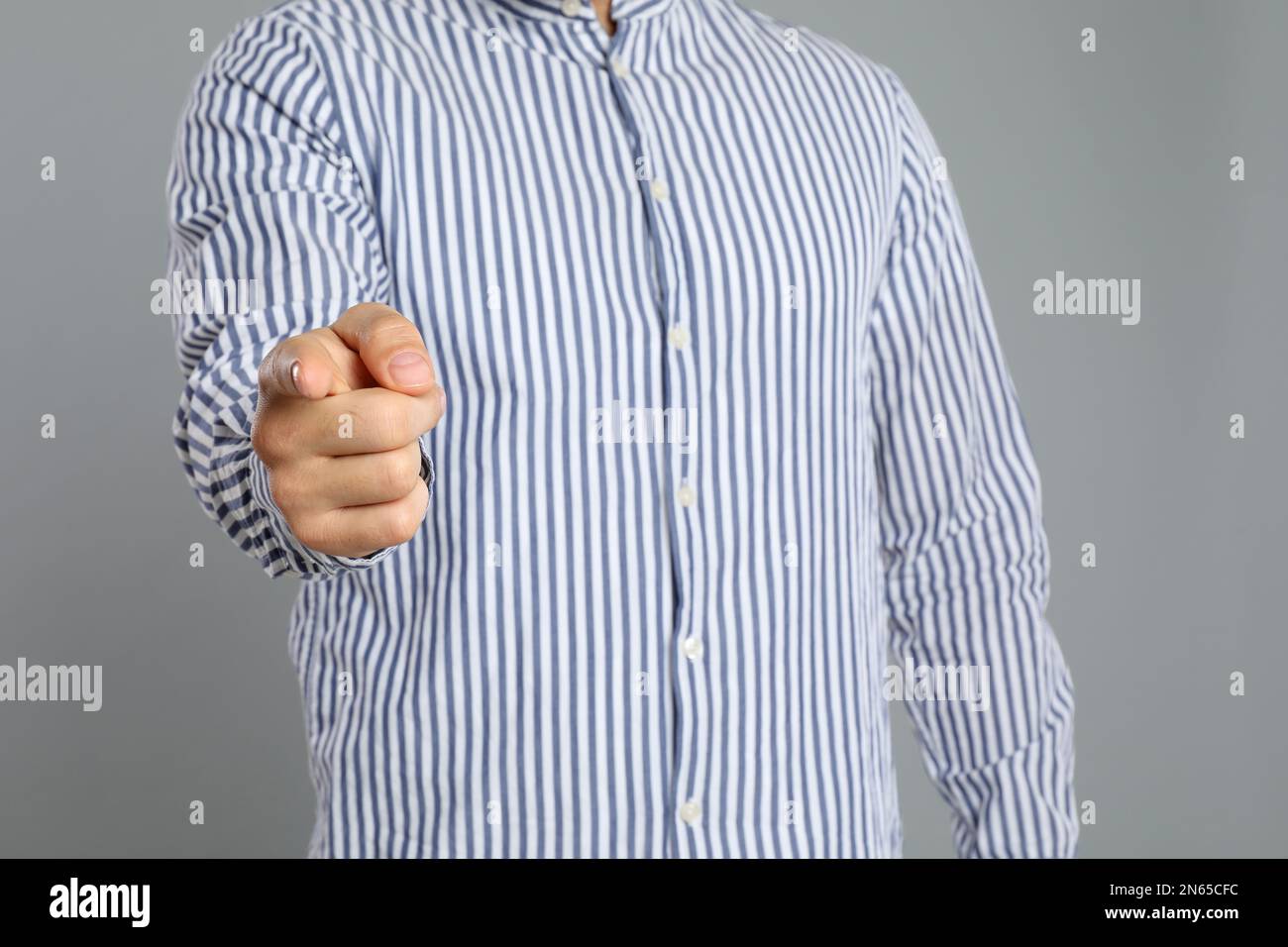 Man touching something on grey background, closeup. Finger gesture ...