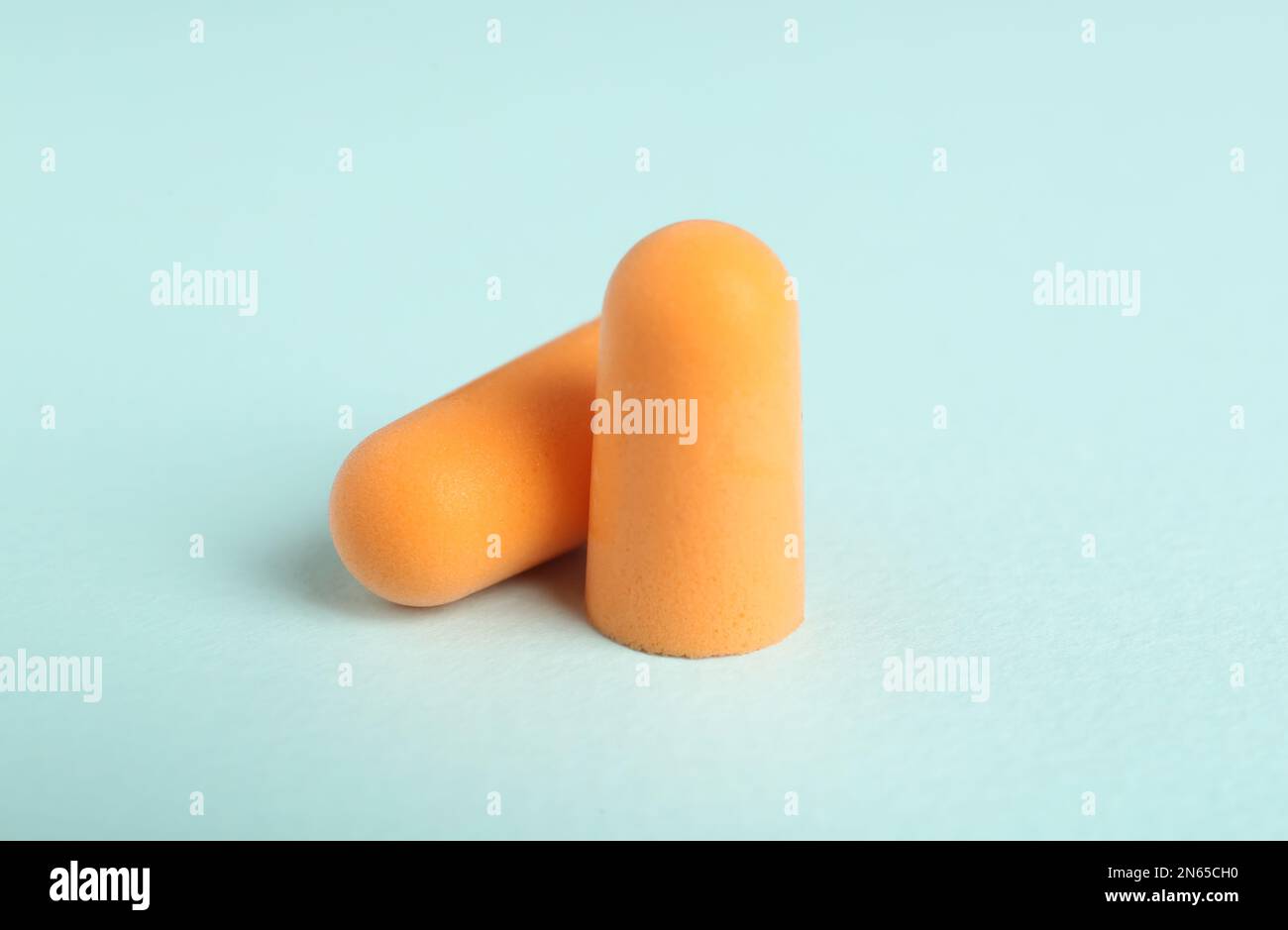 Pair of orange ear plugs on turquoise background Stock Photo - Alamy