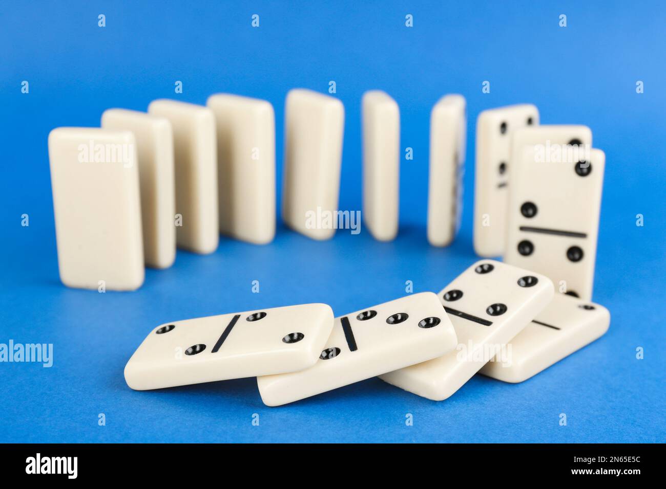 White domino tiles falling on blue background Stock Photo - Alamy