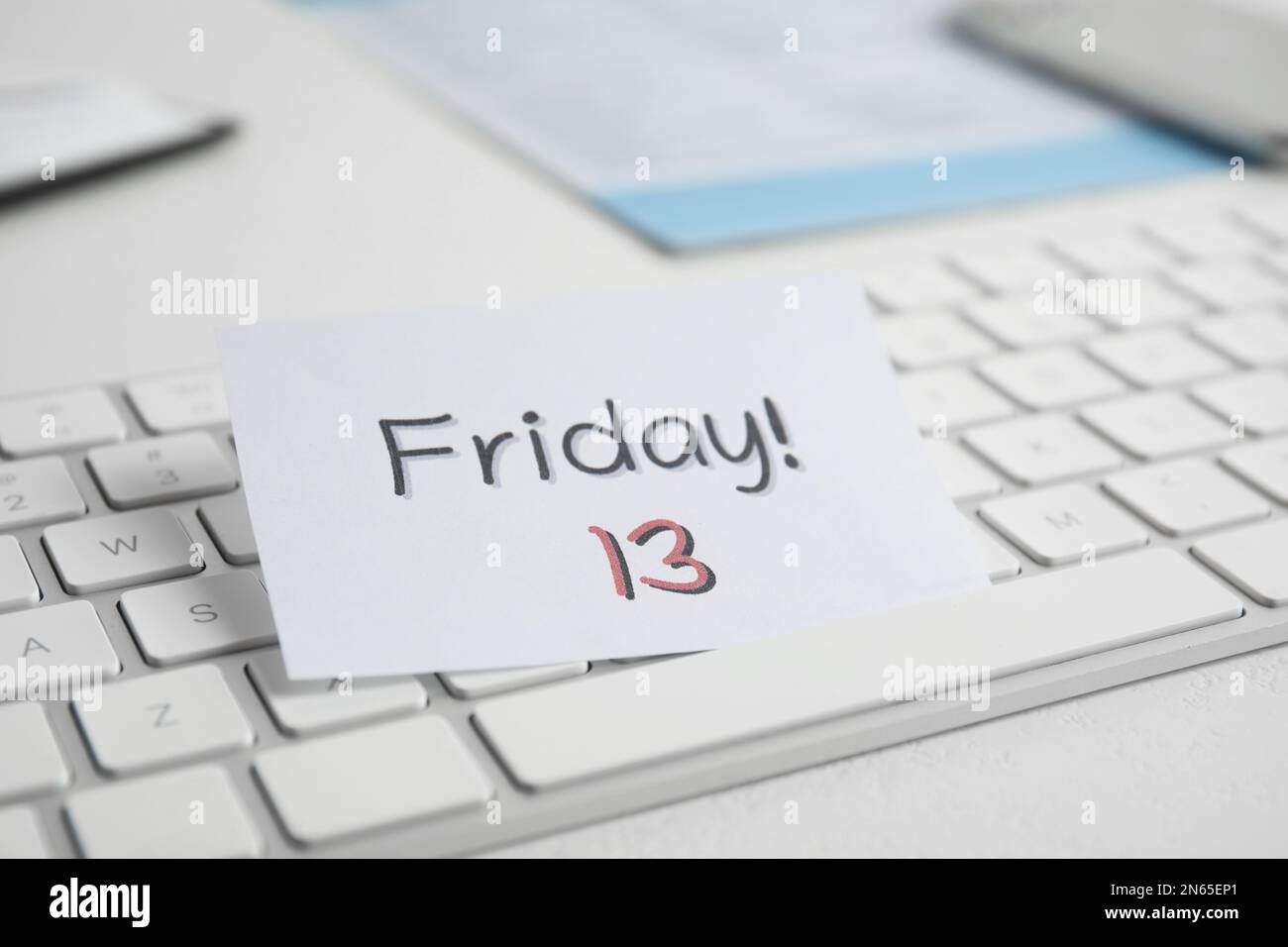 Paper note with phrase Friday 13 and keyboard on white table ...