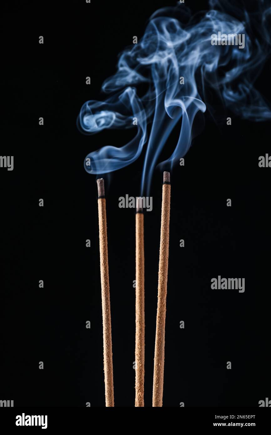Incense sticks smoldering on black background, closeup Stock Photo - Alamy