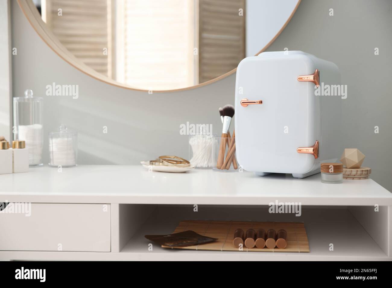 Cosmetics refrigerator and skin care products on white vanity table ...