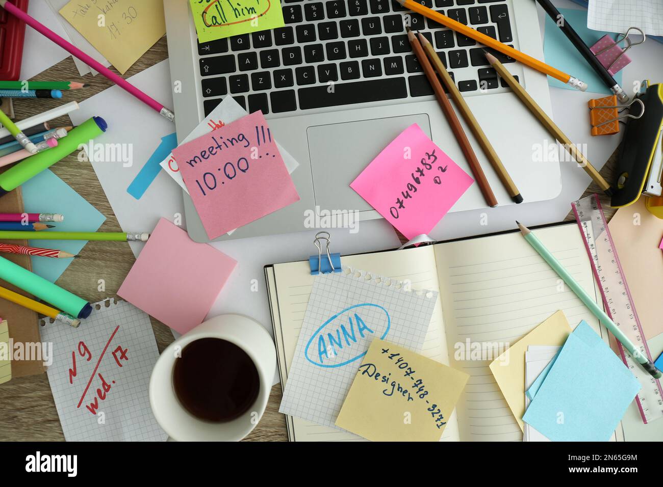 Laptop, notes and office stationery in mess on desk, top view ...