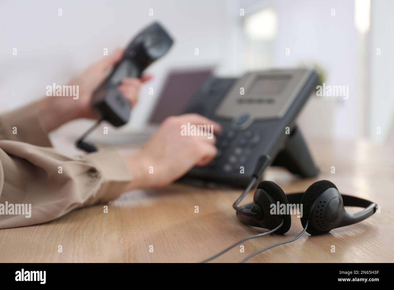 Woman using desktop telephone in office, focus on headset. Hotline ...