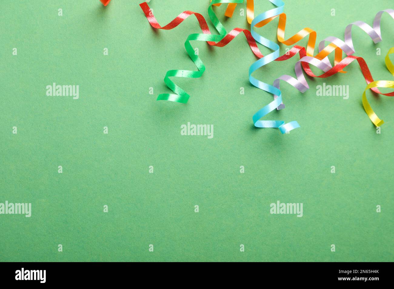 Colorful serpentine streamers on green background, flat lay. Space for ...