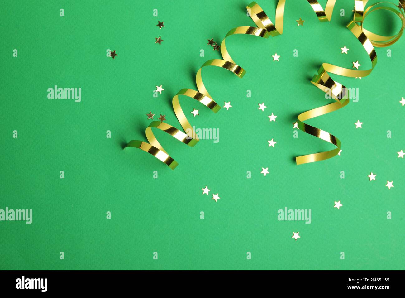 Shiny golden serpentine streamers and confetti on green background ...