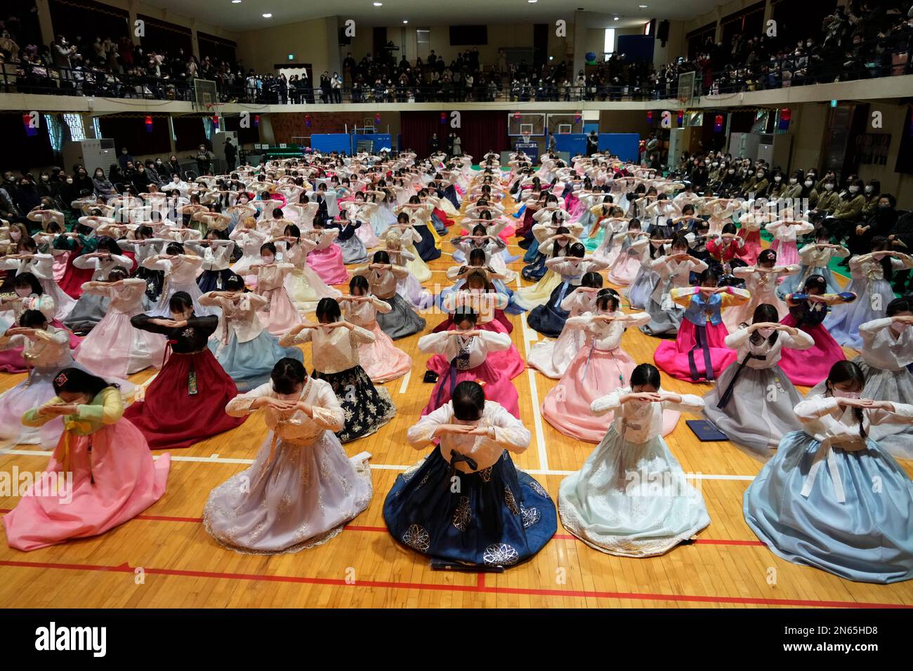 High school seniors clad in traditional attire bow during a joint ...