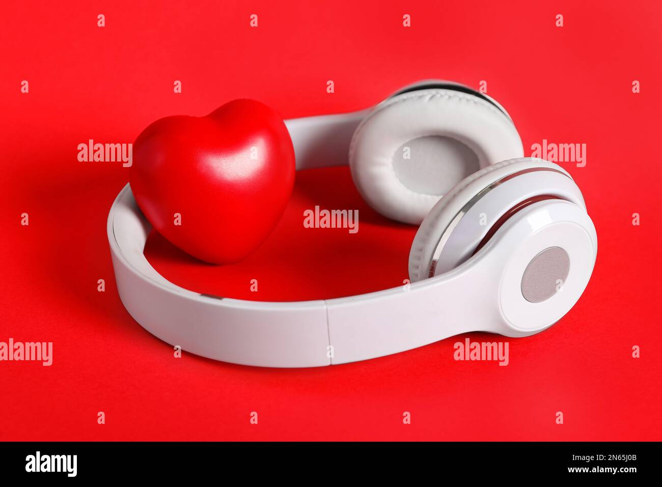 Modern headphones and heart on red background. Listening love music ...