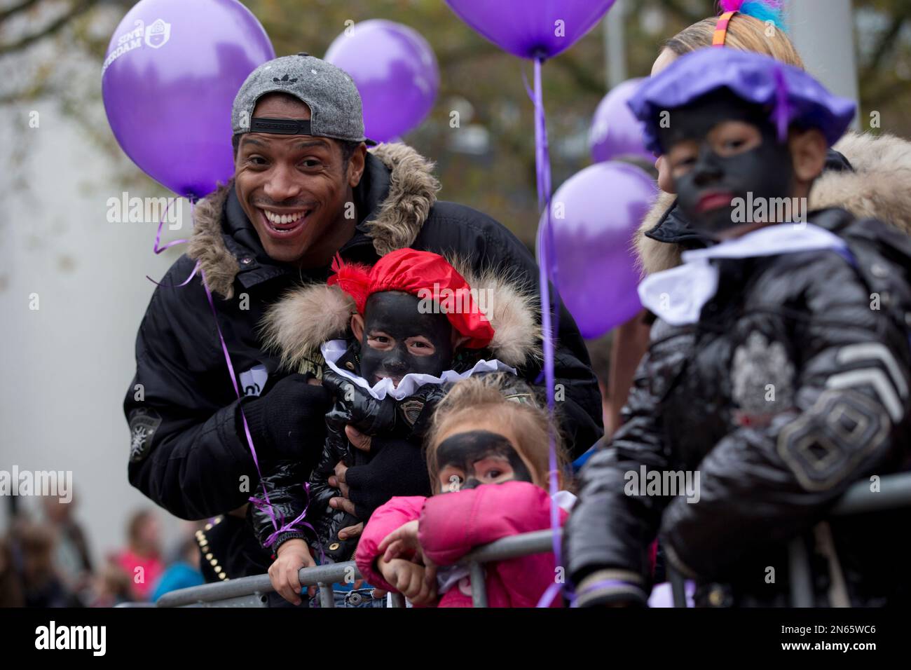 Spectators, some with their faces painted black, wait for the arrival ...