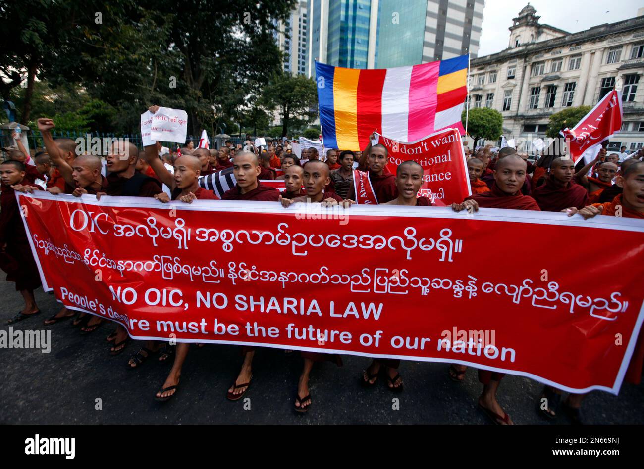 A group of Myanmar Buddhist monks hold a protest banner and shout ...