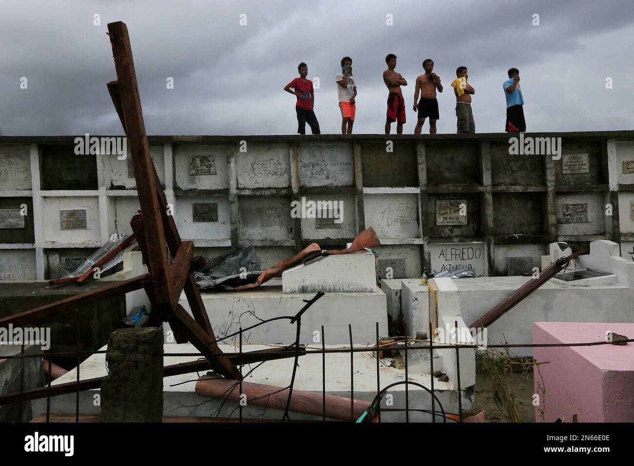 Survivors watch cemetery workers place the bodies of Typhoon victim in ...