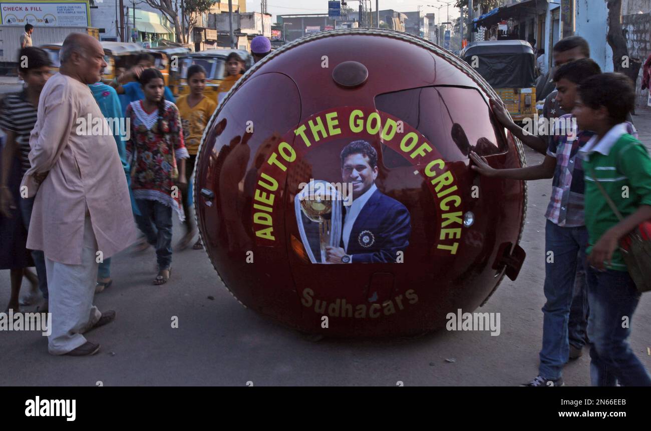Indians look at a cricket ball-shaped car with a portrait of Indian ...