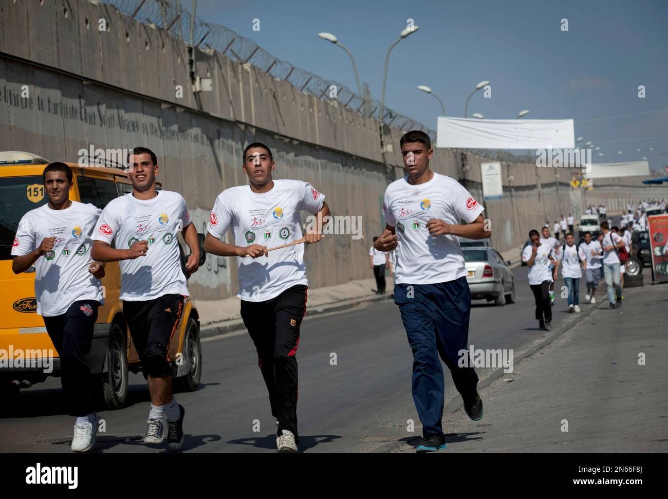 Palestinian runners pass by the separation barrier during the fourth ...