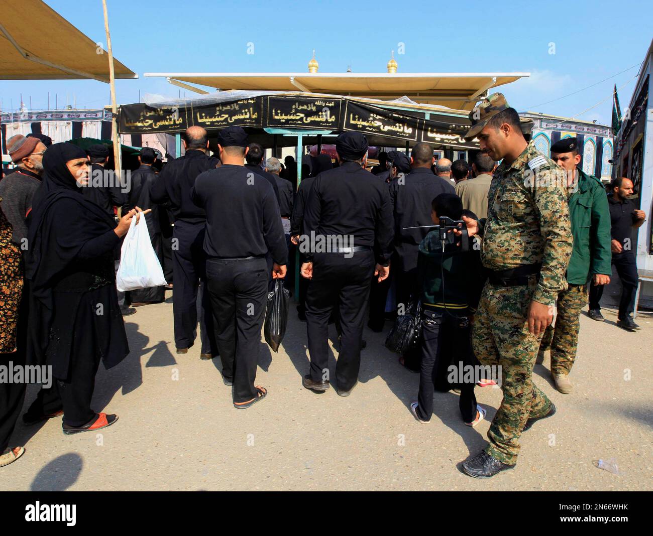 An Iraqi policeman uses a bomb detector to search Shiite worshippers ...