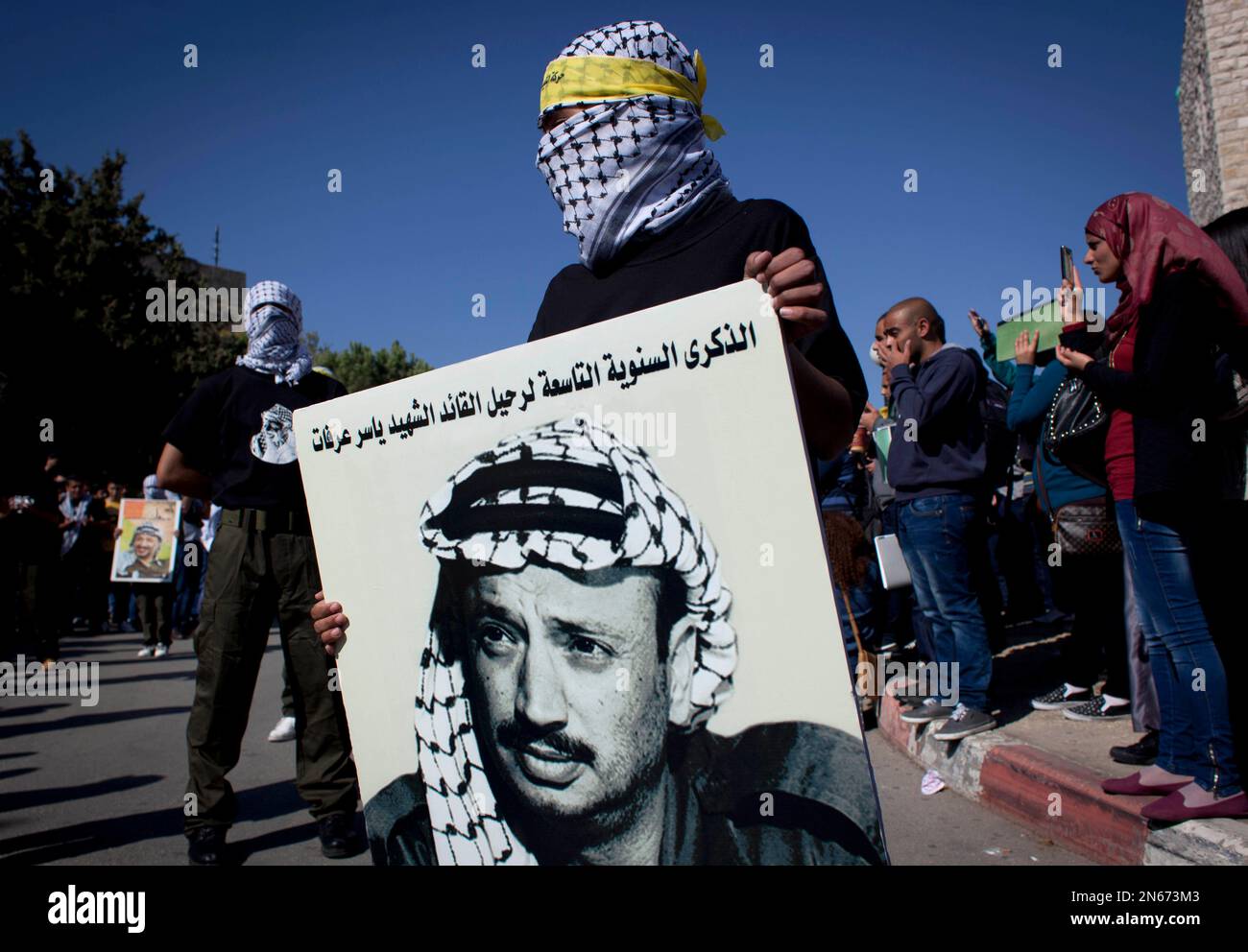 A masked university student carries a poster with a picture of late ...