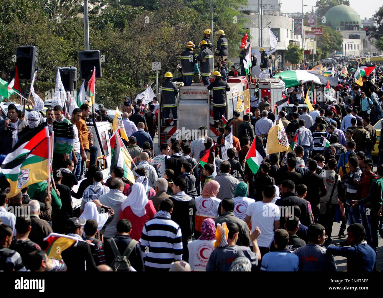 Palestinians wave national flags, during a ceremony marking the 9th ...