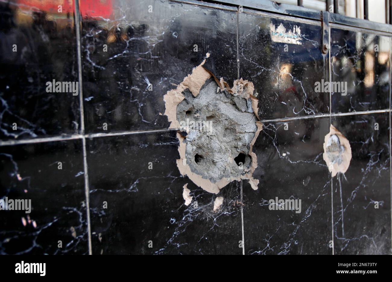 Shadows of local residents are reflected on a bullet-riddled wall of an ...