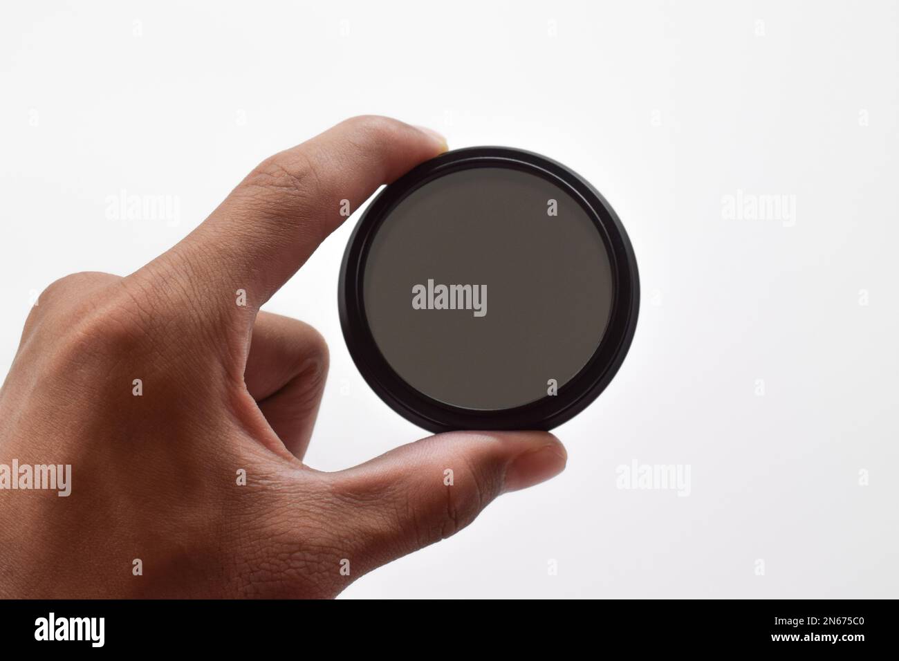 Man's hand holds a ND (neutral density) optical filter isolated on ...