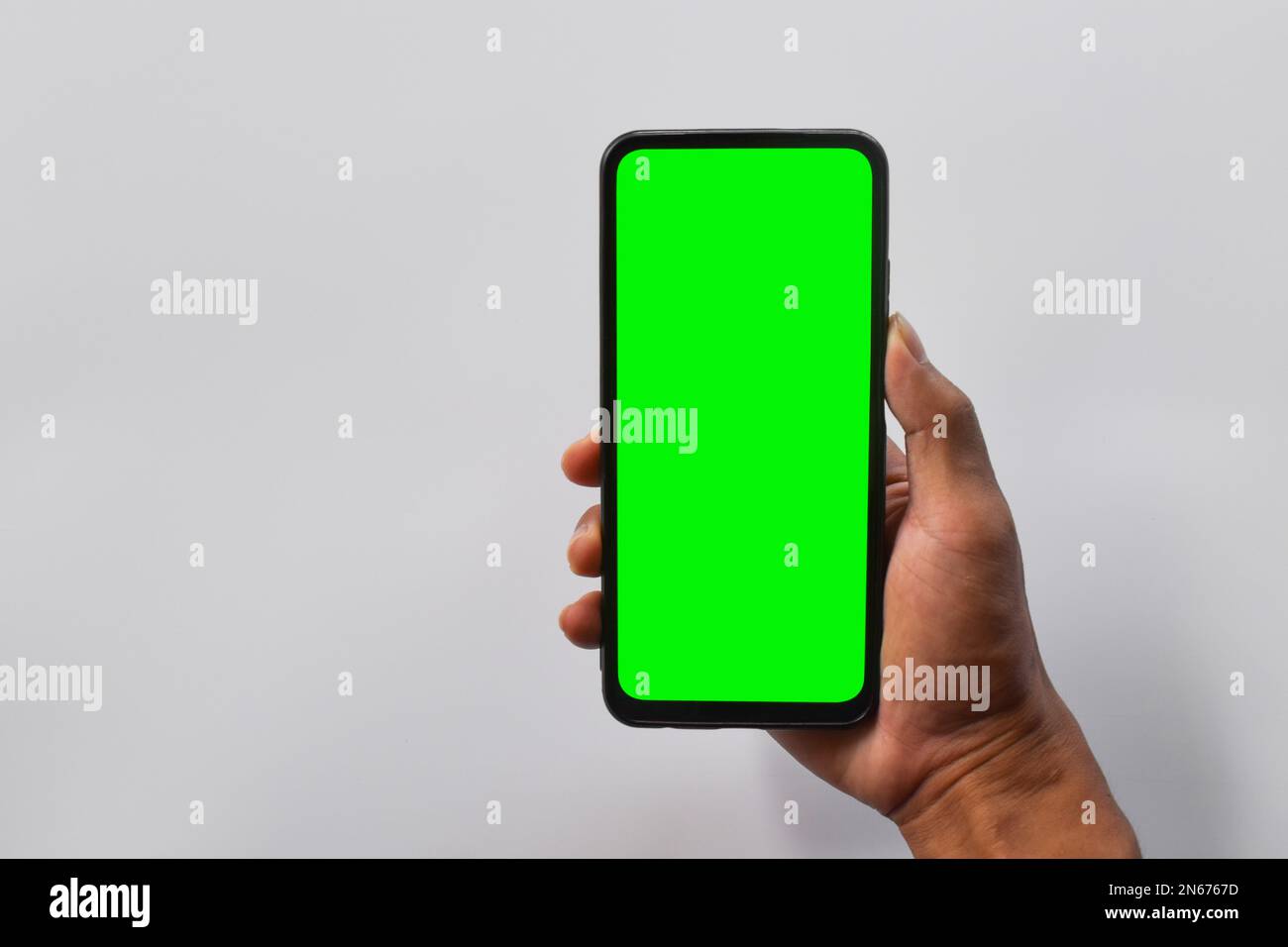 Mock up mobile. Man's hand holding black smartphone with green screen ...