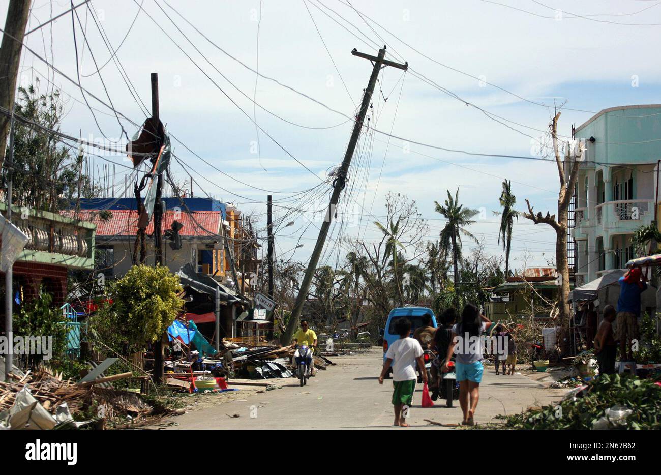 Residents walk past the devastation caused by Typhoon Haiyan, Sunday ...