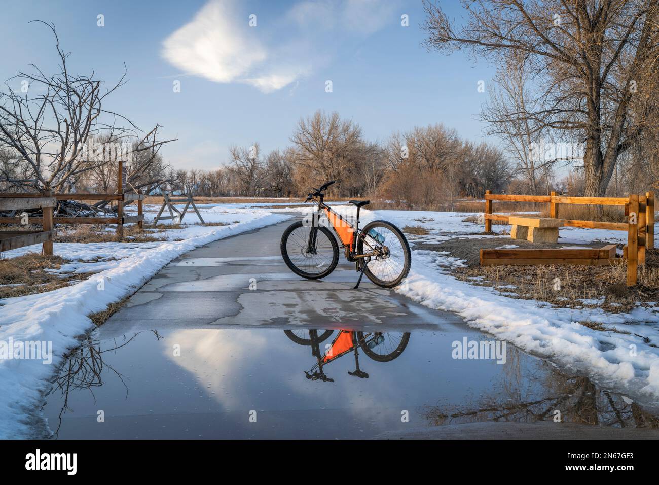 mountain bike on Poudre River Trail near Greeley in Colorado, winter scenery with puddle ...