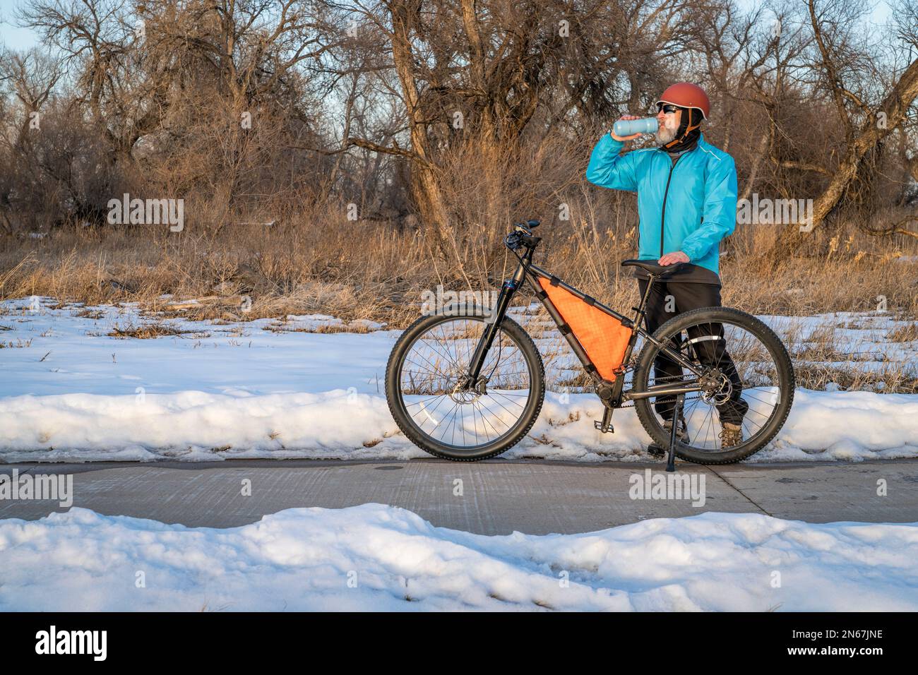 senior cyclist with a mountain bike is taking a rest stop on Poudre ...