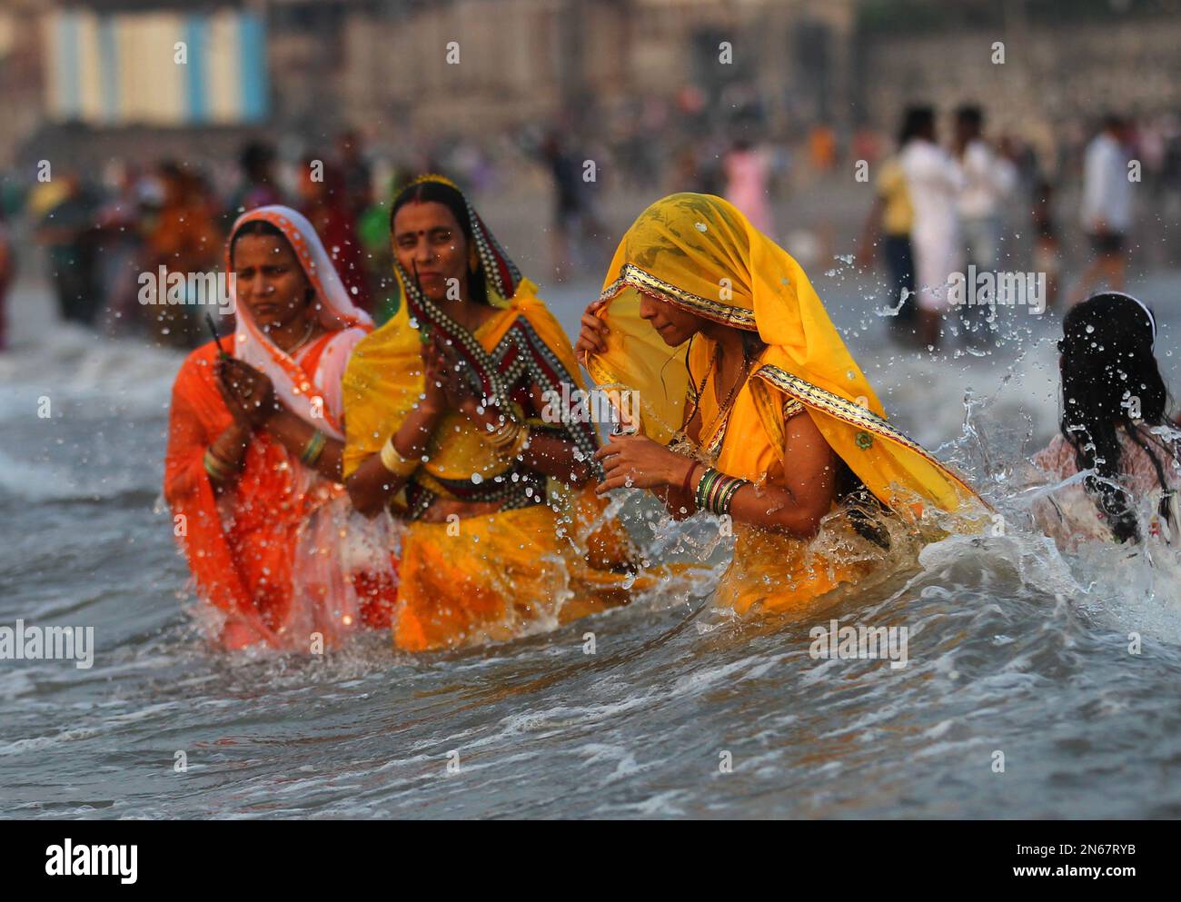 Waves splash water on Hindu devotees performing rituals at sunset ...