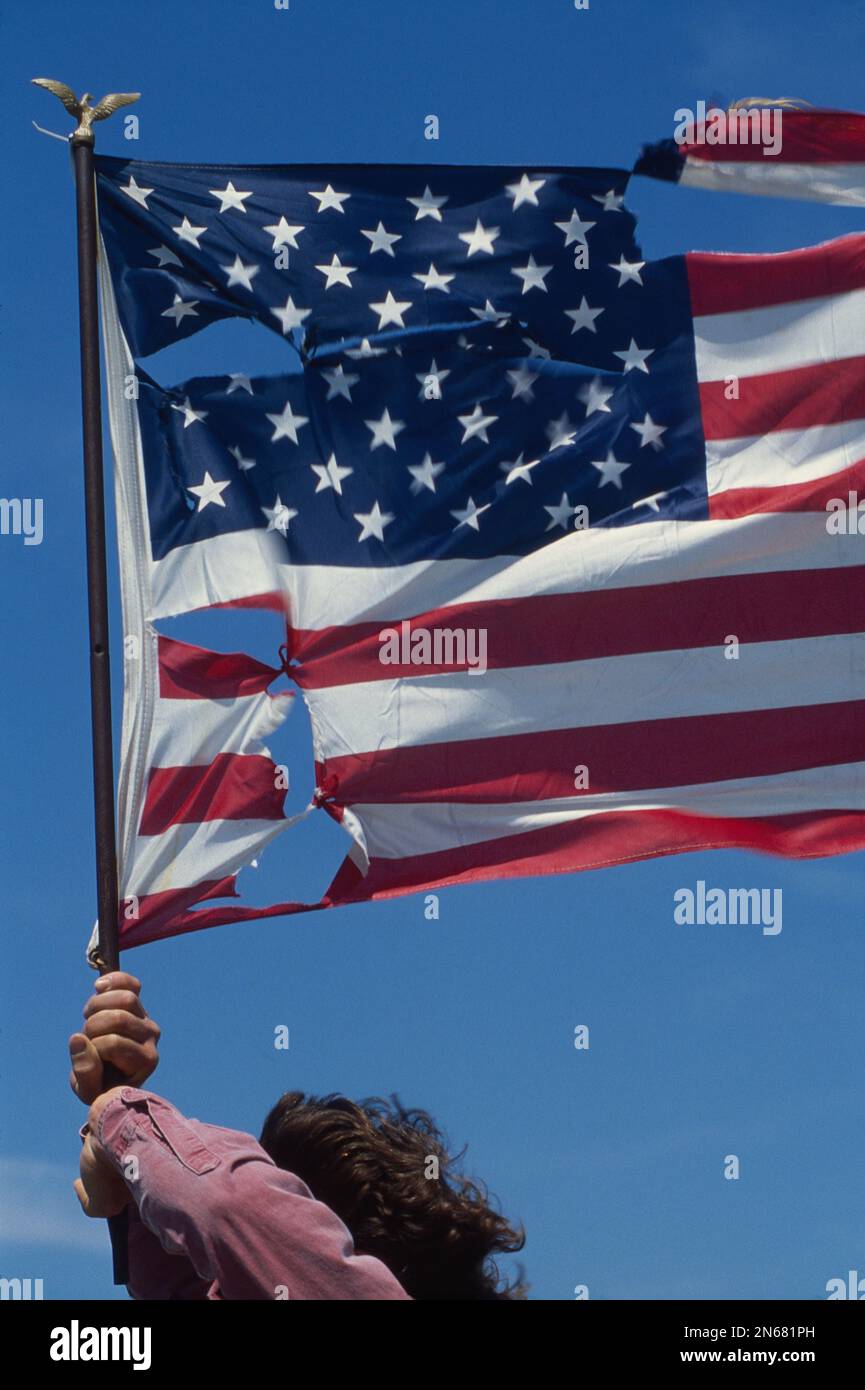Someone carrying a shredded US flag as it blows in the wind Stock Photo ...