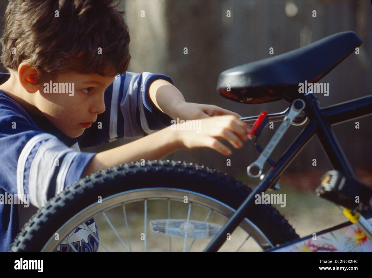 Young boy working on fixing his bike with tools Stock Photo - Alamy