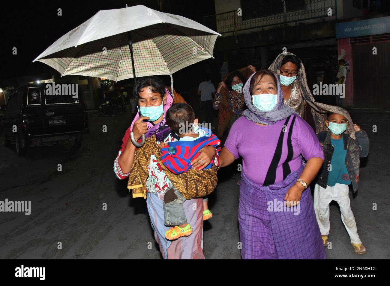 Villagers wear masks to protect themselves from volcanic ash from the ...