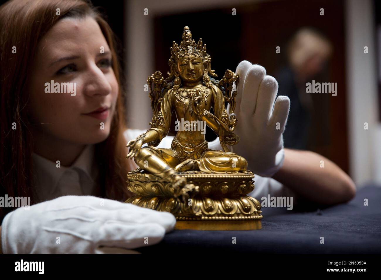 A Sotheby's employee poses for photographs with a gilt-bronze figure of ...