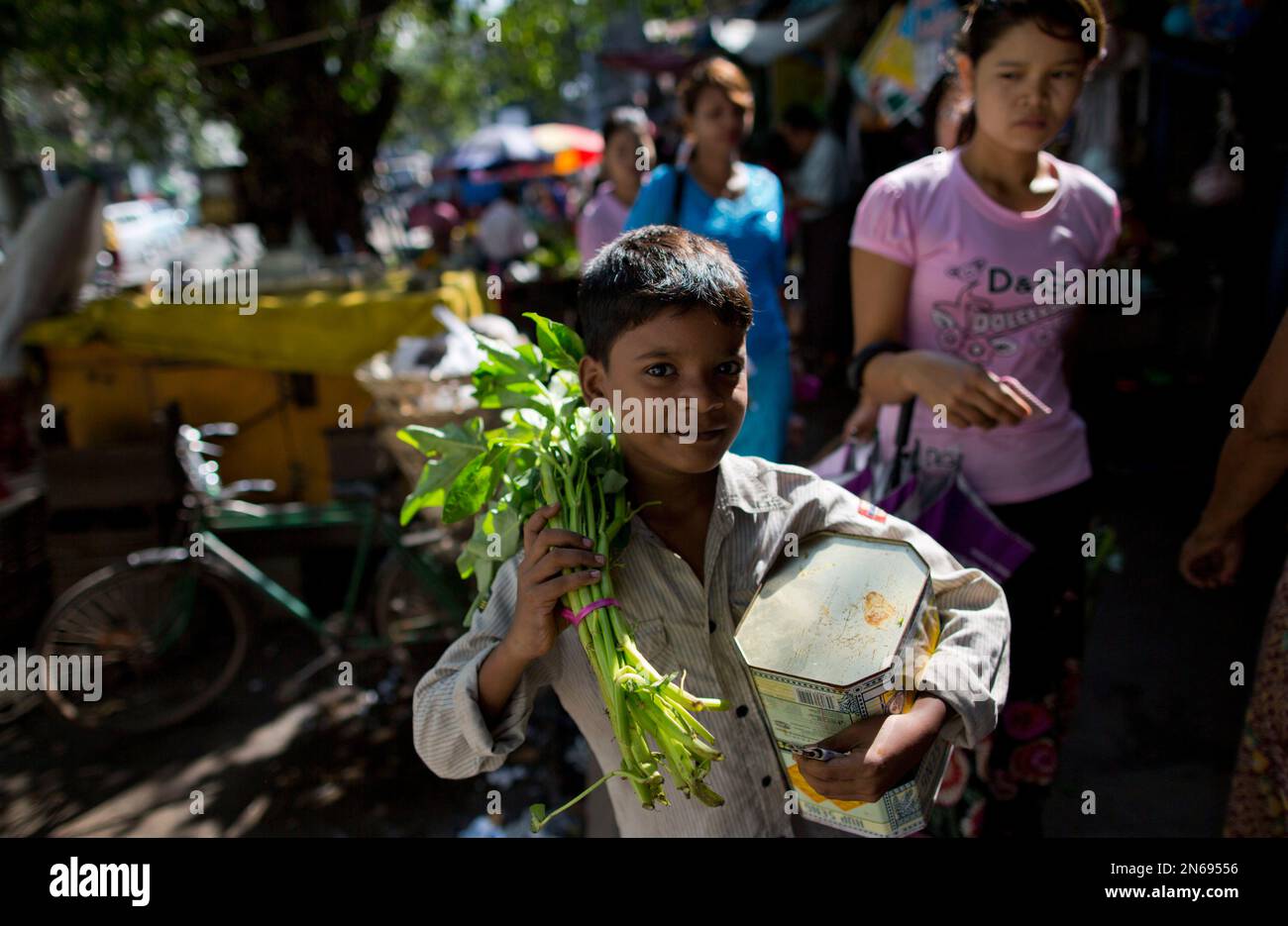 A Myanmar boy walks with a bundle of water-crest in a Yangon street, Myanmar Friday, Nov. 1 ...