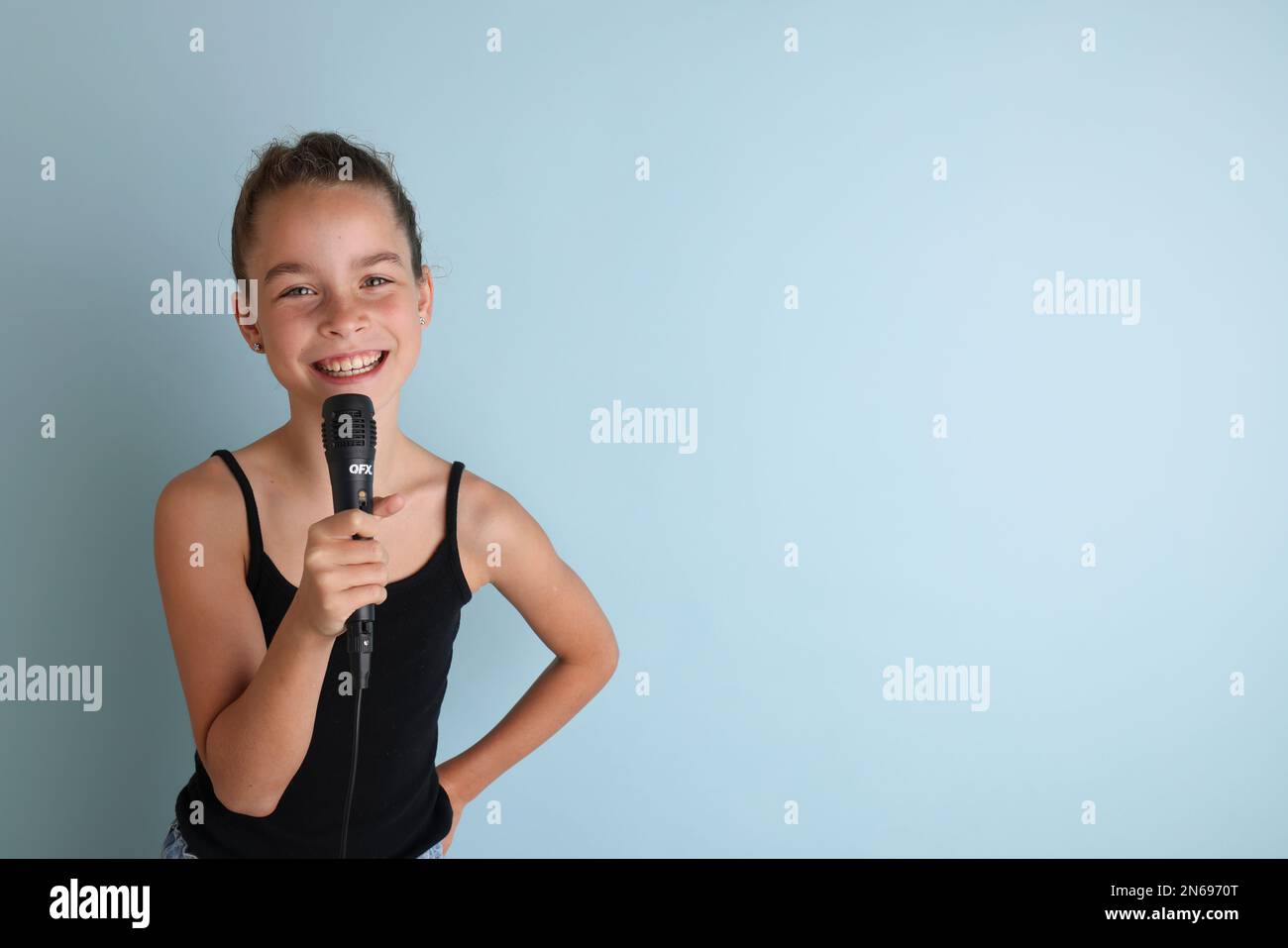 Portrait of a cute teenage girl singing, using microphone. Teenage girl ...