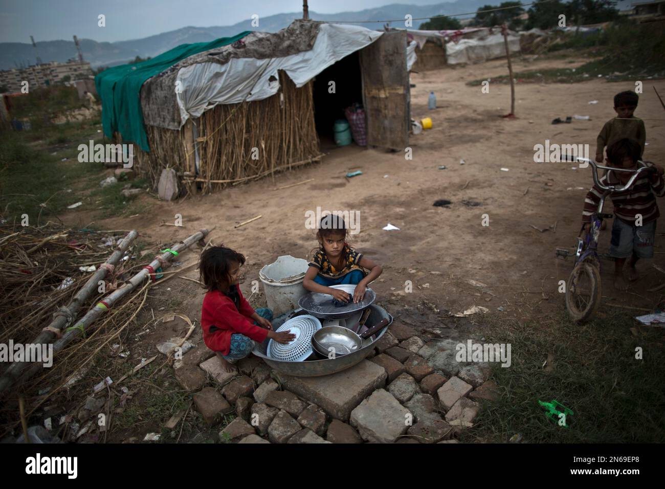Pakistani girls wash their kitchen equipment outside their family's ...