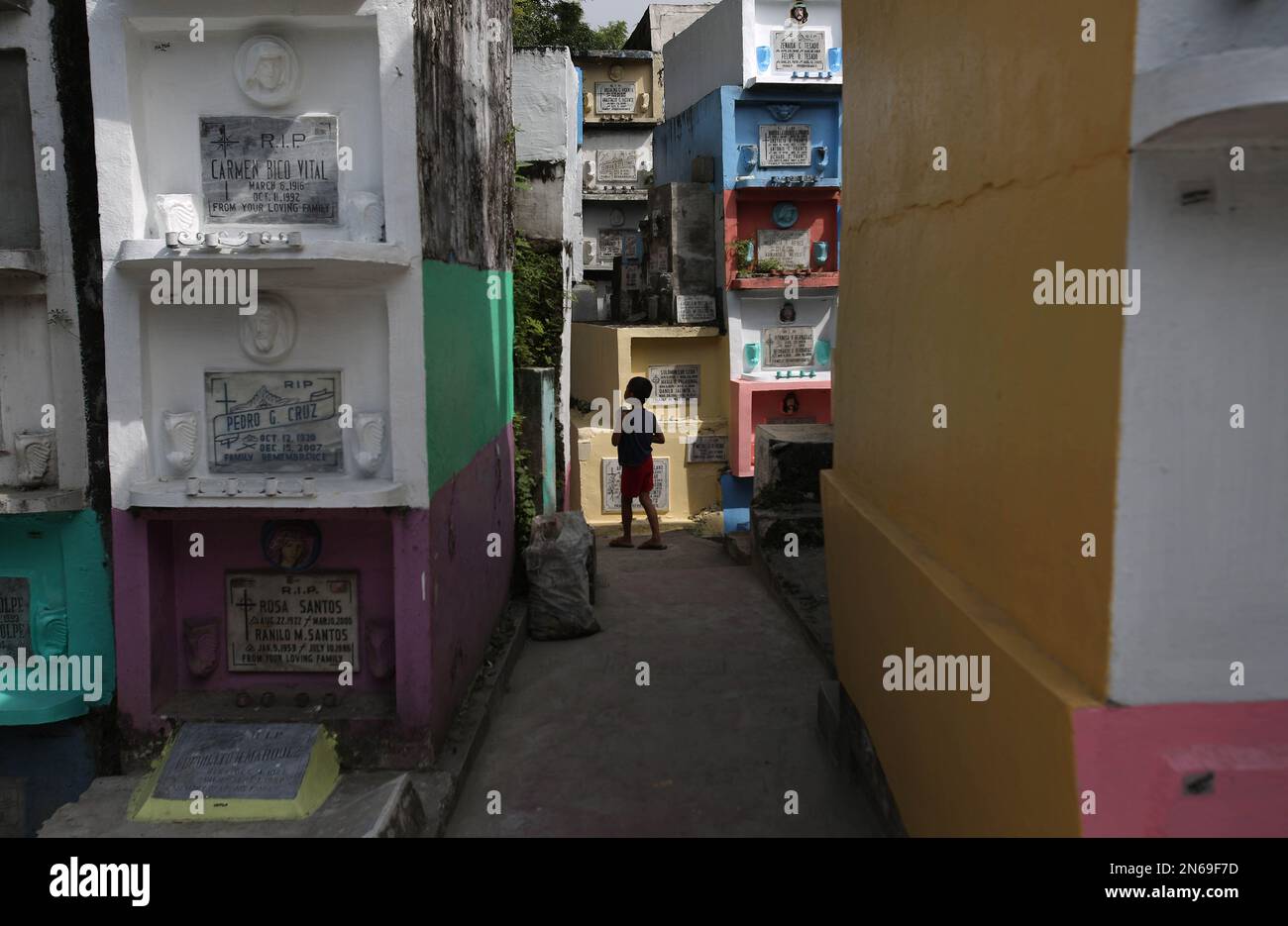 A Filipino boy walks past layers of tombs at a hillside Barangka public ...