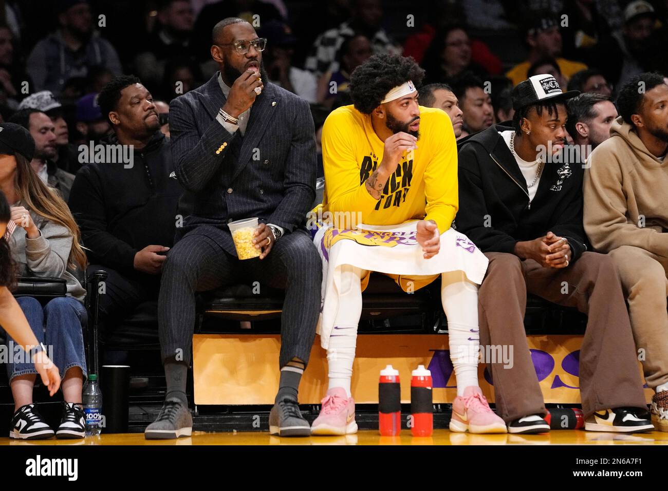 Los Angeles Lakers' LeBron James, left, eats popcorn as he sits next to ...