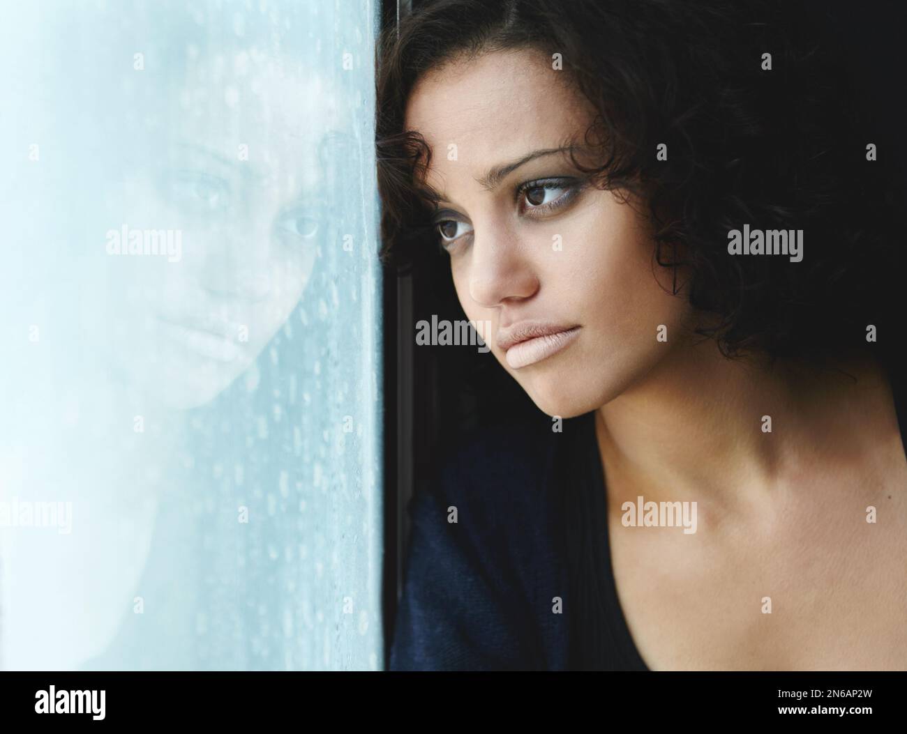 The dark side of depression. A sad young woman sitting by a window ...