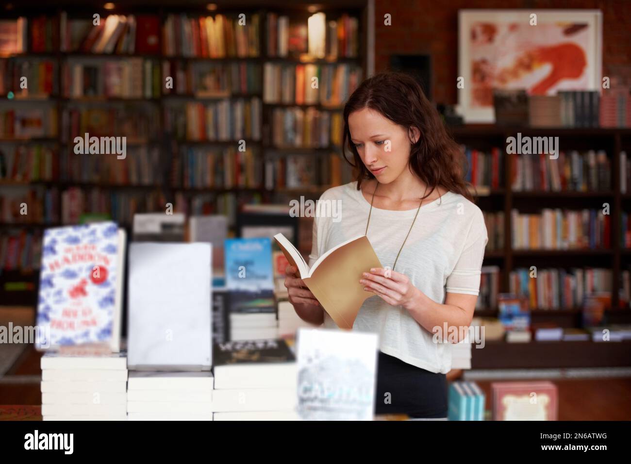 Browsing the bestsellers. A young woman browsing the stacks of books in ...
